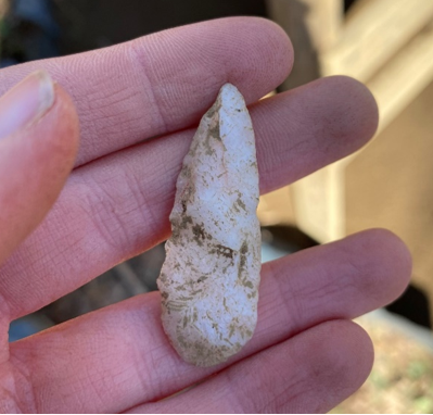 Hand holding white quartz projectile point
